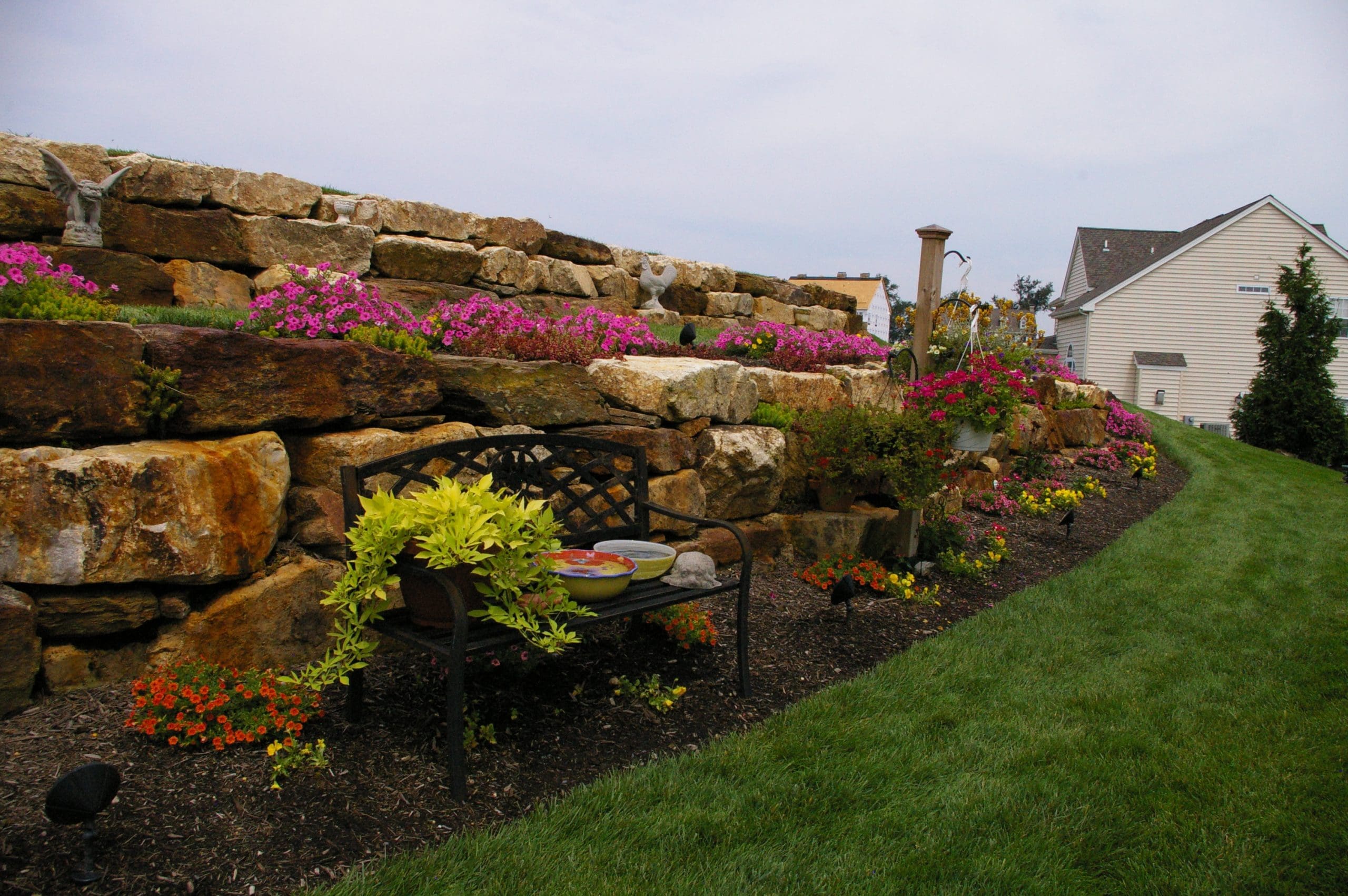 Tiered Boulder Retaining Wall with Vibrant Flowers and Garden Seating